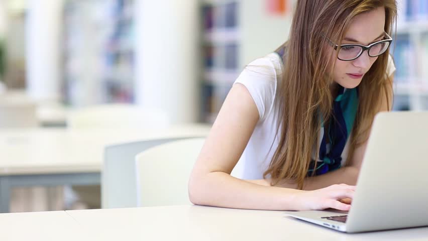 Young Female Student Working Alone In A Campus Library, Bored With ...