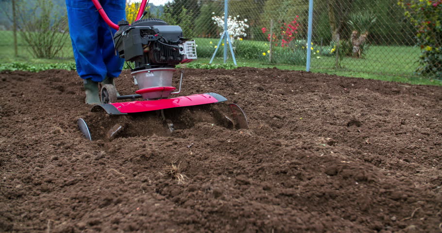 A Senior Man Is Slowly Plowing His Garden With A Cultivator Which ...