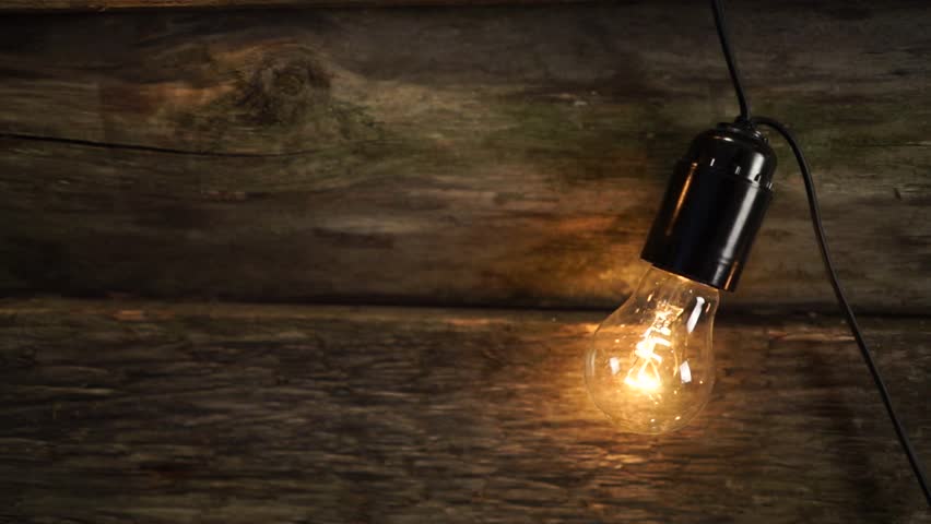 Stock Video Clip of Glowing bulb on the brown wooden background ...