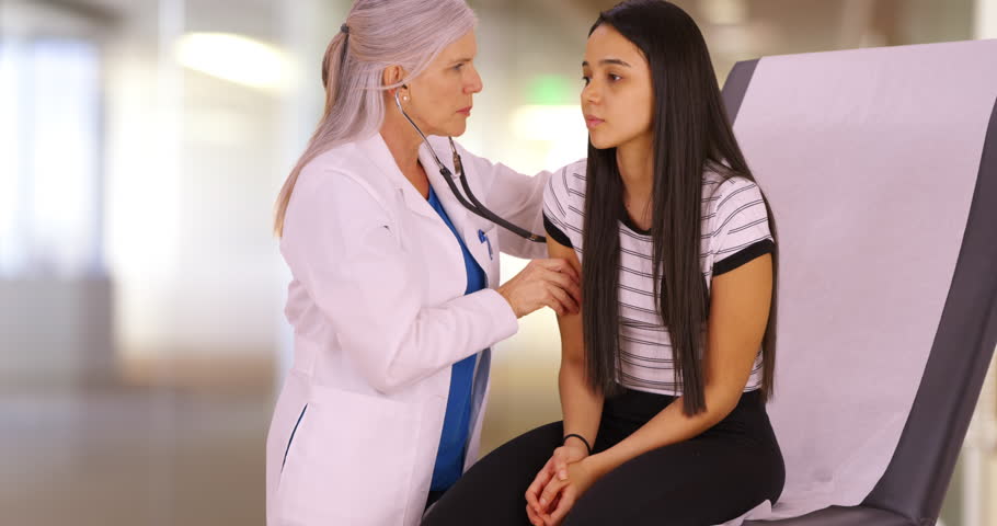 A Young Teen Girl Receives A Medical Exam. An Elderly Doctor Gives A ...