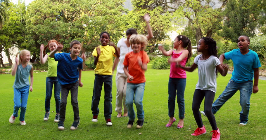 Pretty Teacher Jumping Up With Young Pupils Outside The School In Slow ...